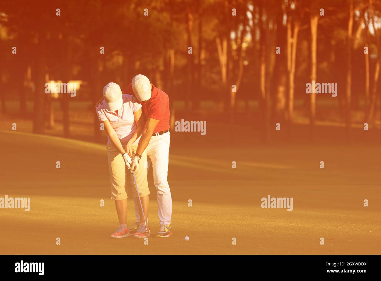 male golf instructor teaching female golf player, personal trainer ...