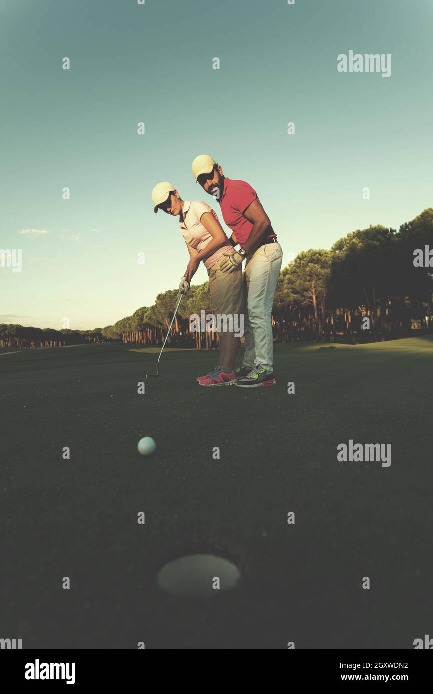 male golf instructor teaching female golf player, personal trainer ...