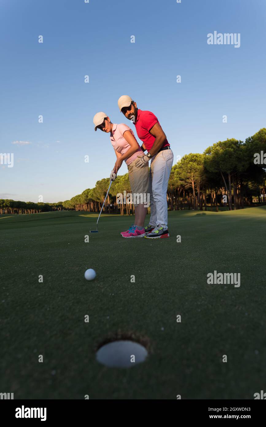male golf instructor teaching female golf player, personal trainer ...