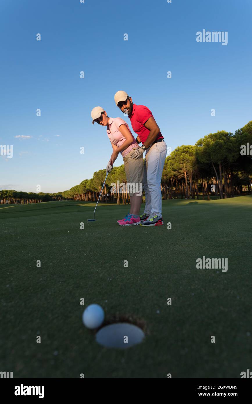 male golf instructor teaching female golf player, personal trainer ...