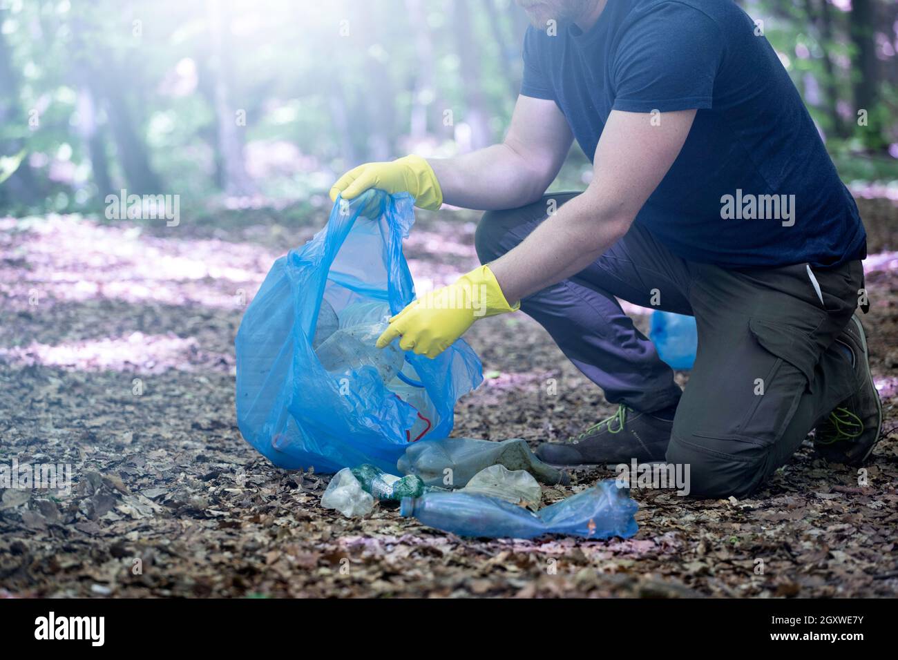 Hand picking up garbage plastic for cleaning the woods or parks ...