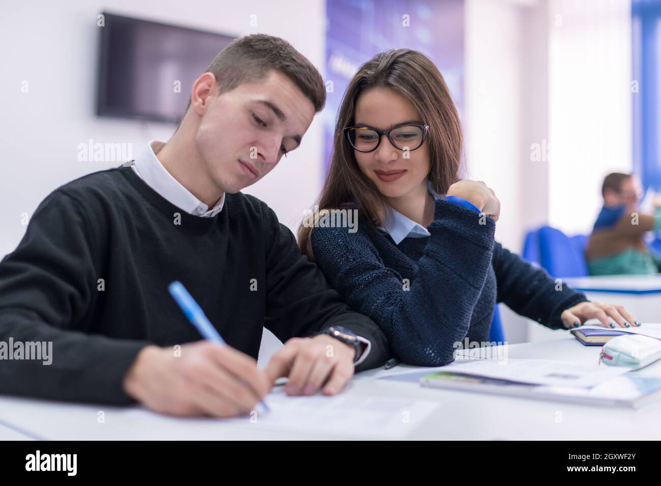 Two young students man and woman with others working on a project in a ...