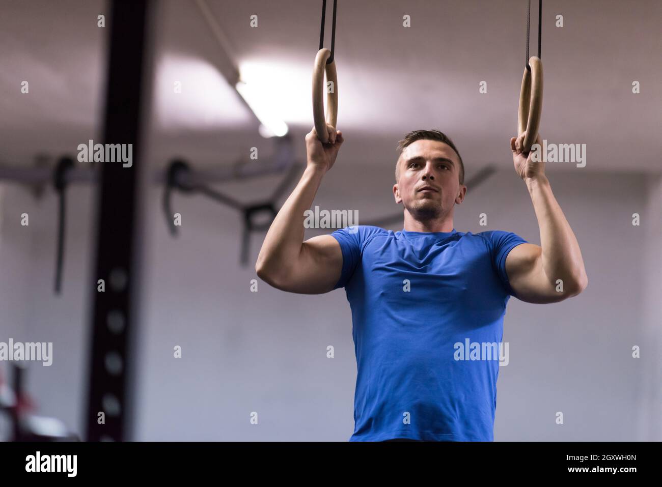 Fitness handsome man doing dipping exercise using rings in the gym ...