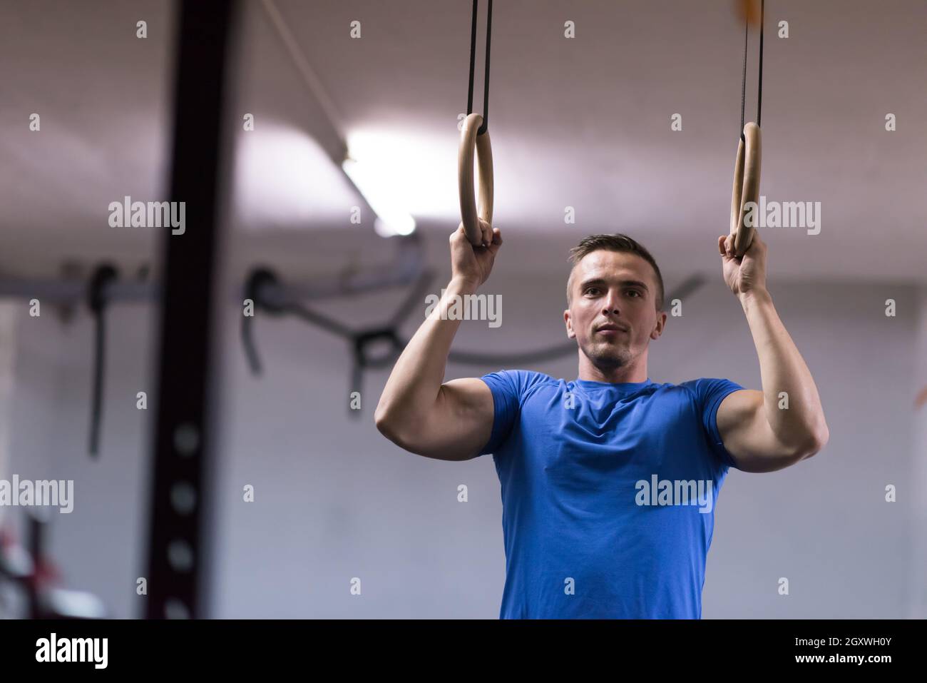 Fitness handsome man doing dipping exercise using rings in the gym ...