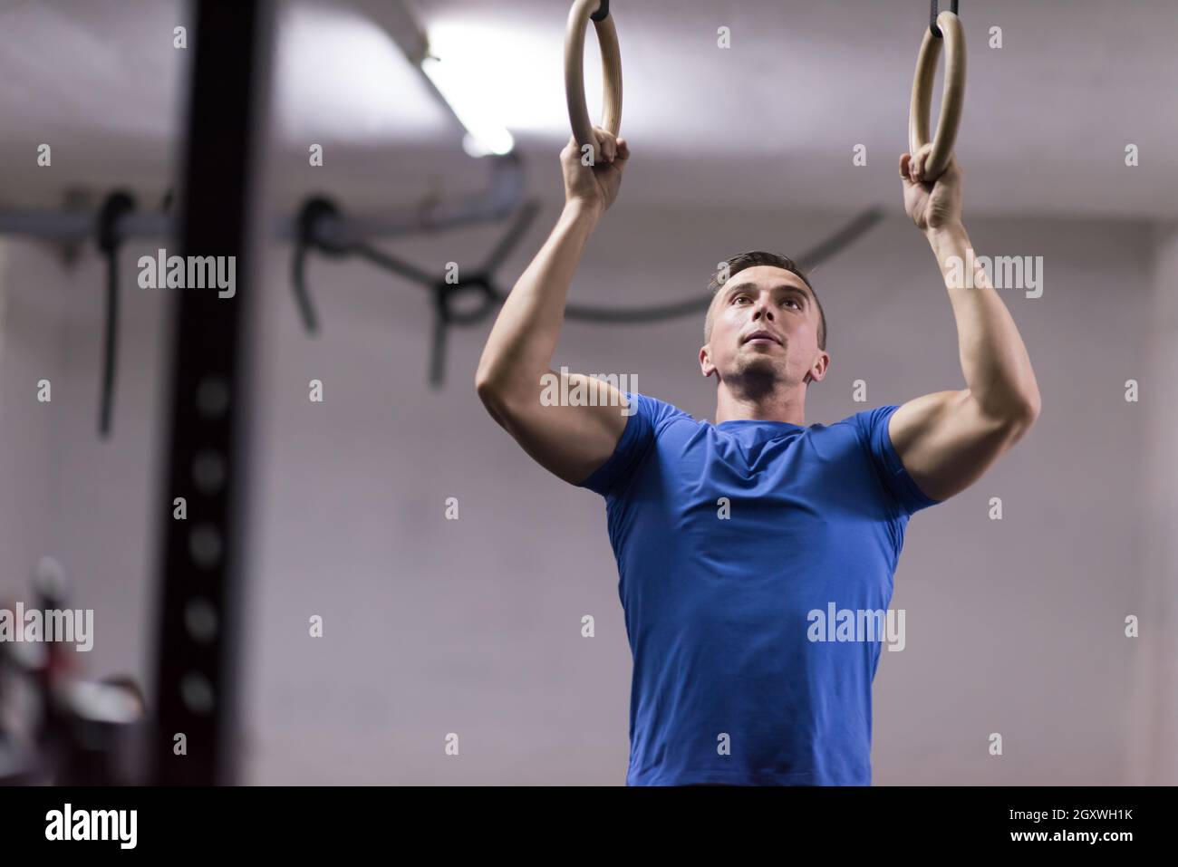 Fitness handsome man doing dipping exercise using rings in the gym ...