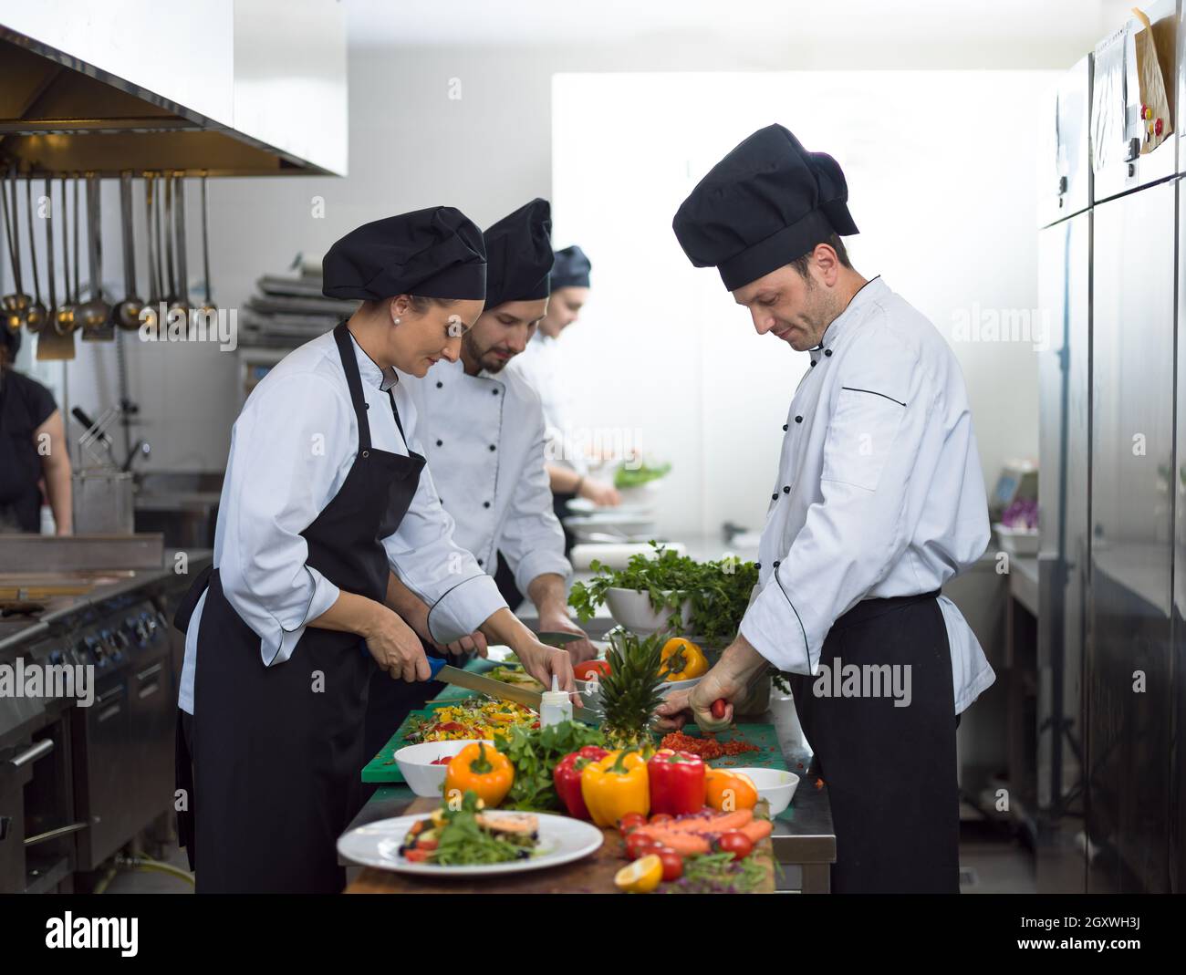 Professional team cooks and chefs preparing meals at busy hotel or ...