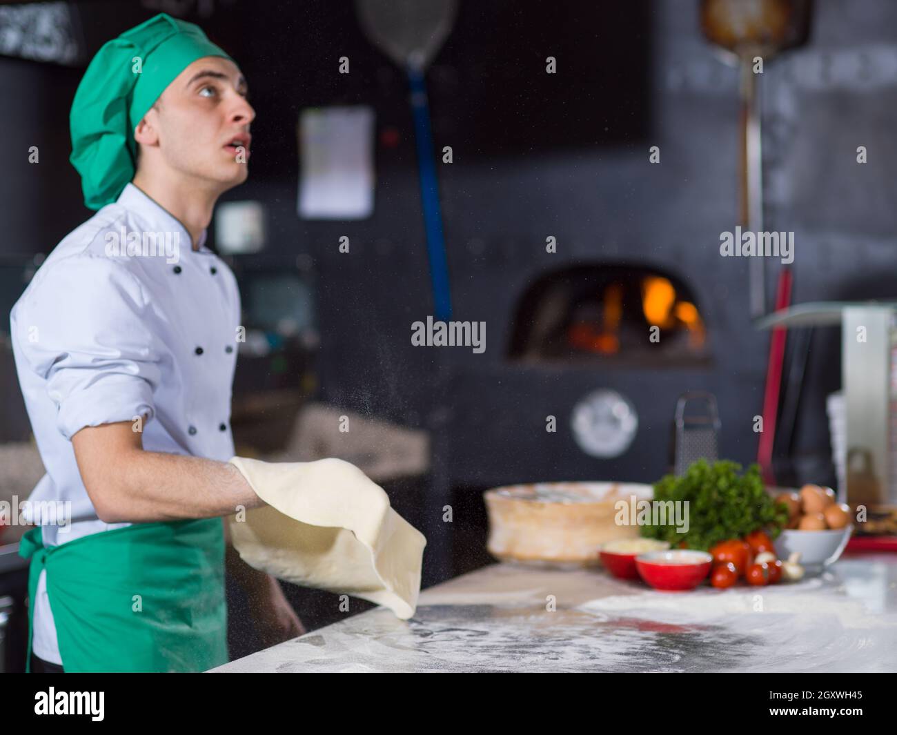 Skilled chef preparing dough for pizza rolling with hands and throwing ...