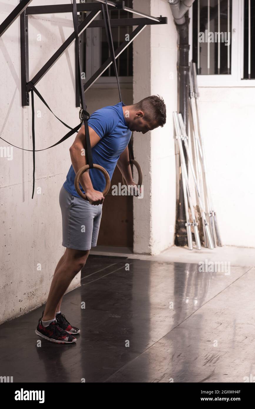 Fitness handsome man doing dipping exercise using rings in the gym ...