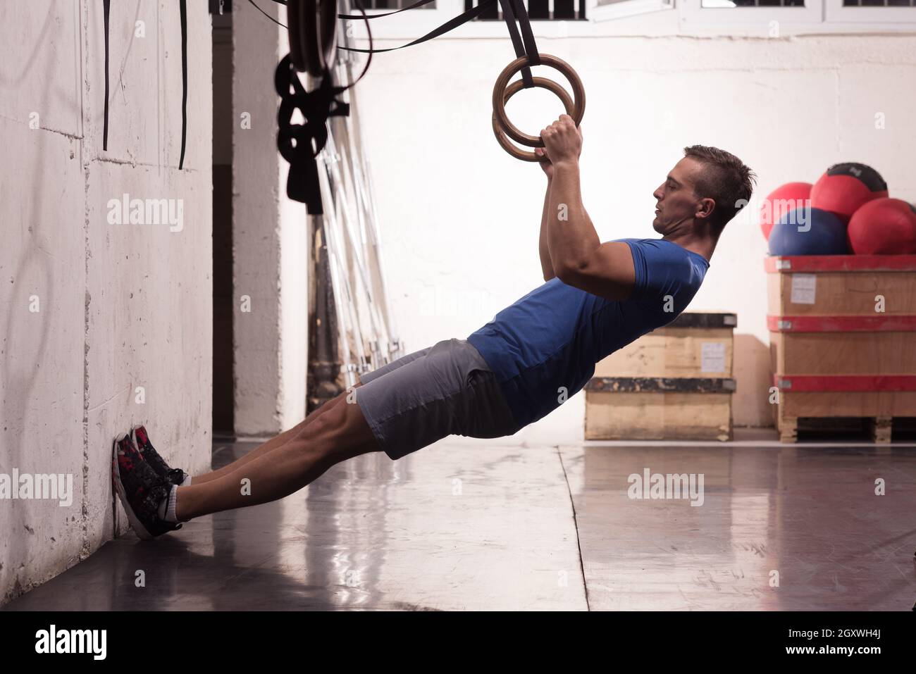 Fitness handsome man doing dipping exercise using rings in the gym ...