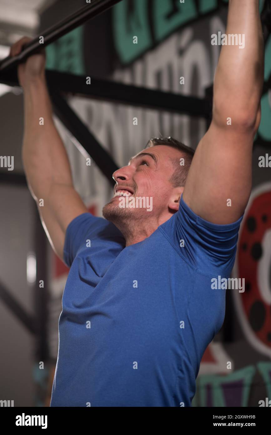 strong young man doing pull ups on a bar in a gym Stock Photo - Alamy