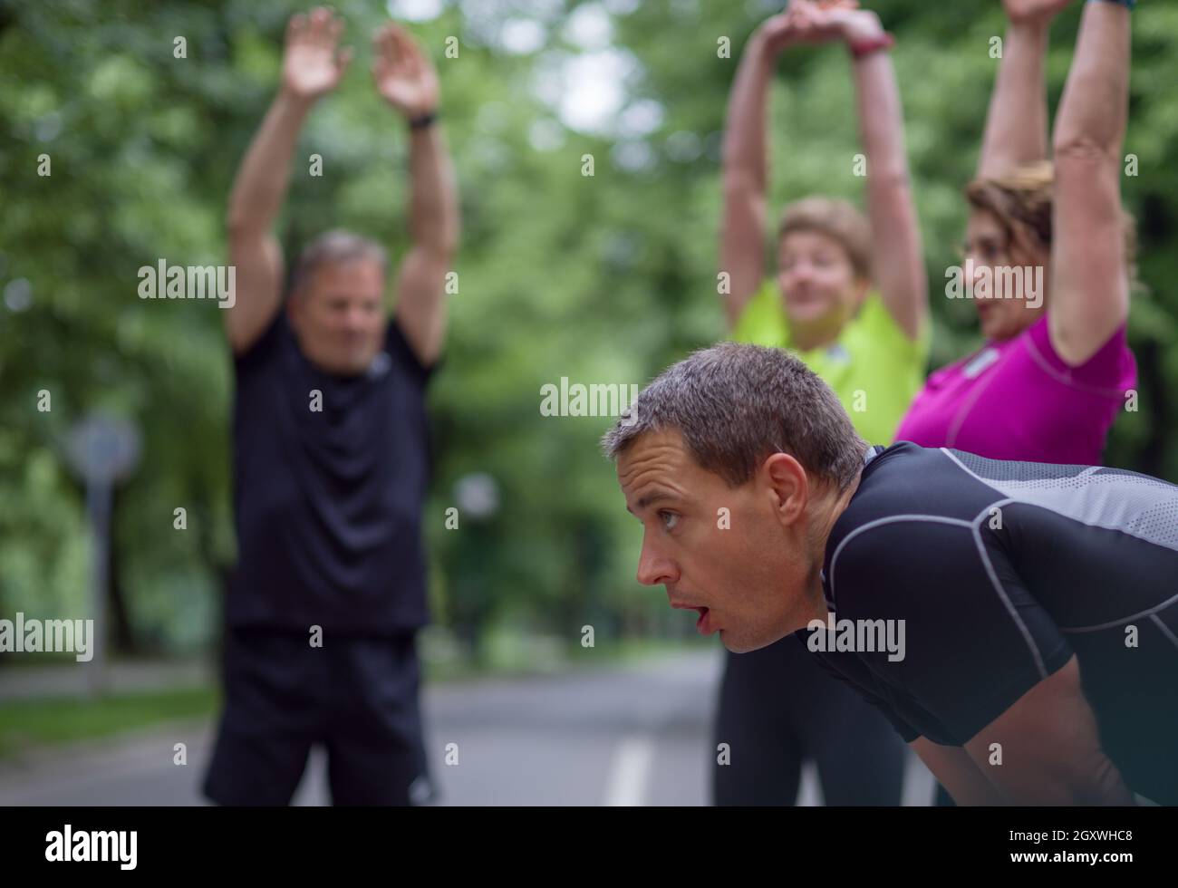 healthy runners team warming up and stretching in city park before ...