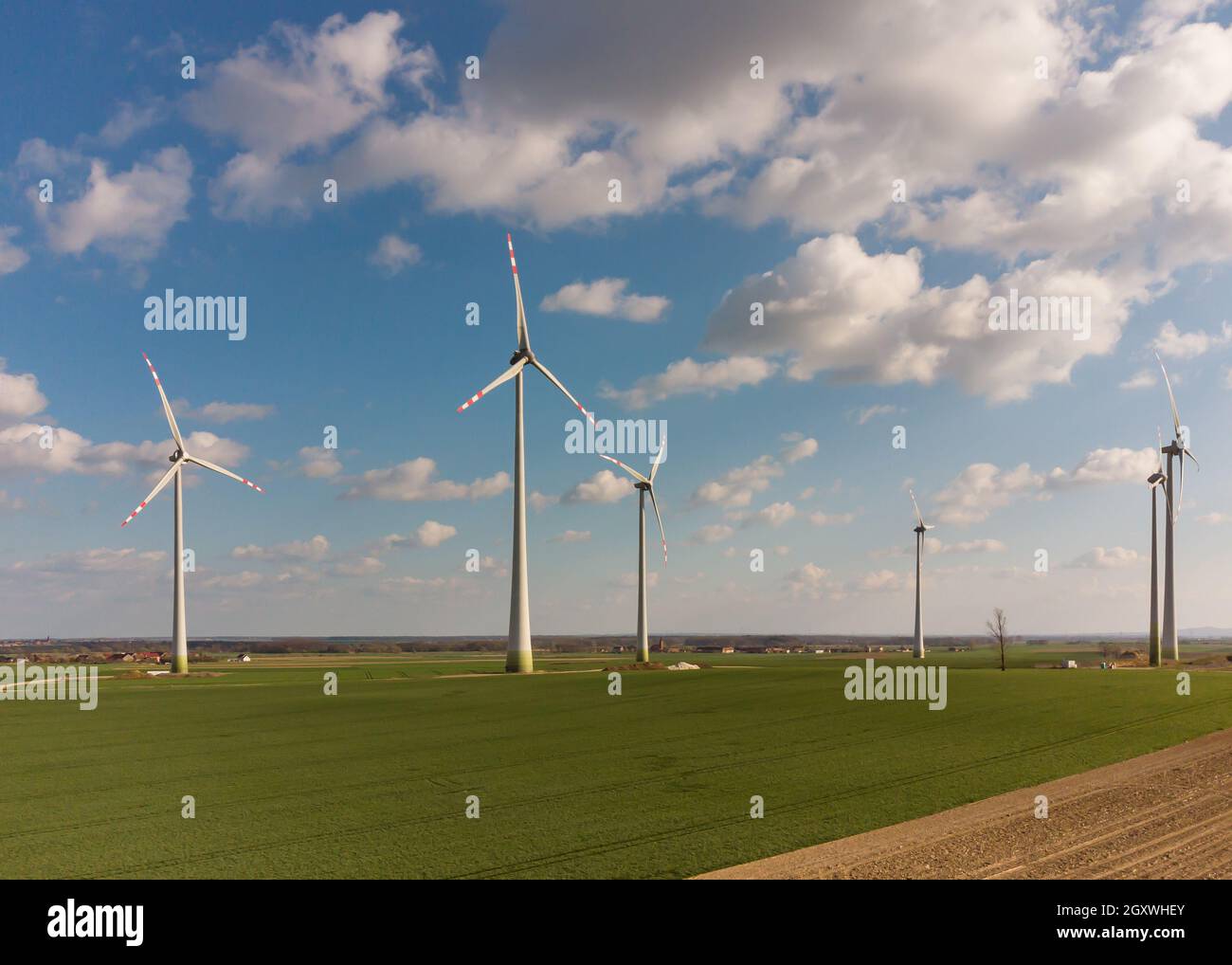 Aerial view of large wind turbines with blades in field against blue ...
