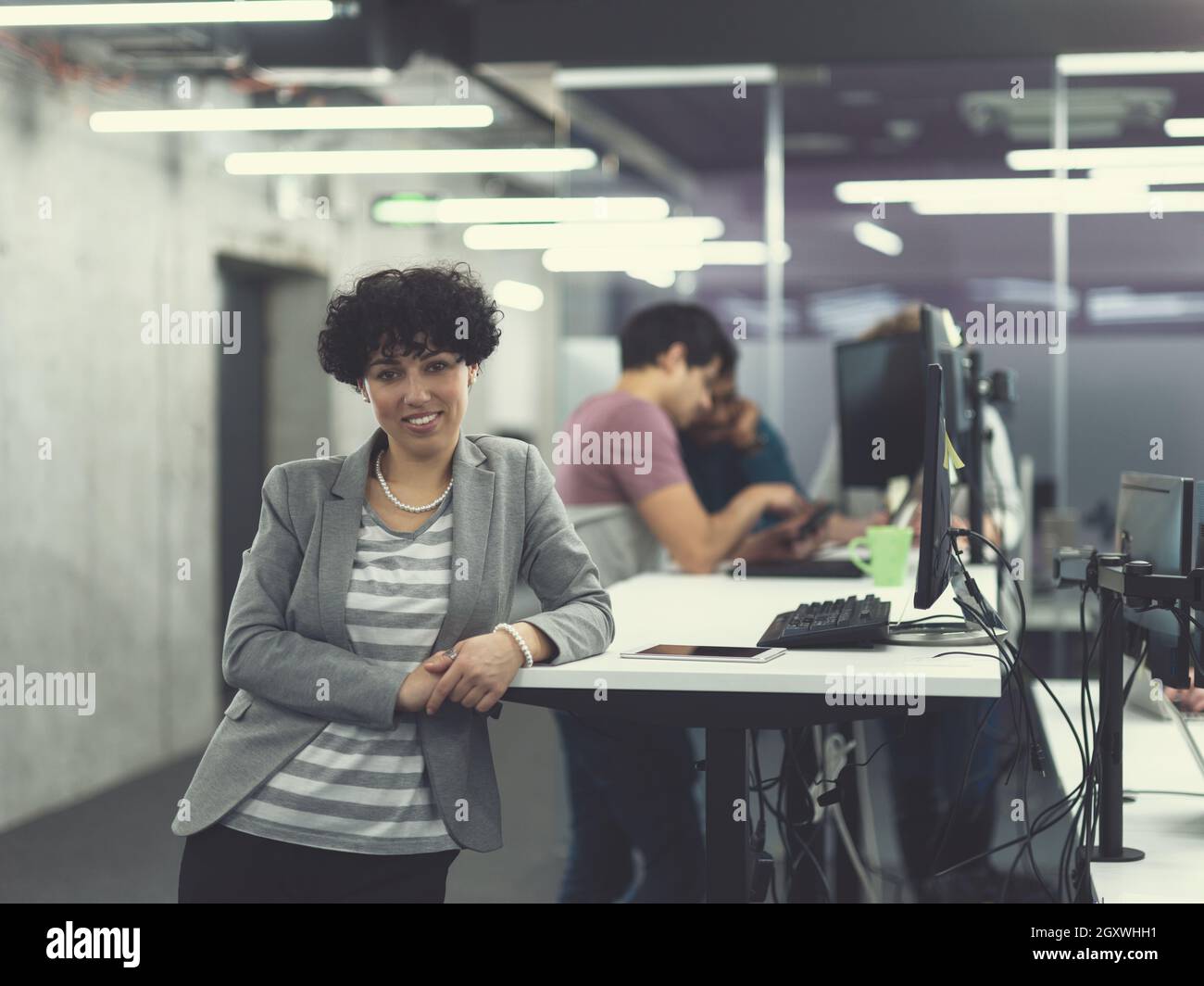 portrait of young female software developer at busy startup office with ...
