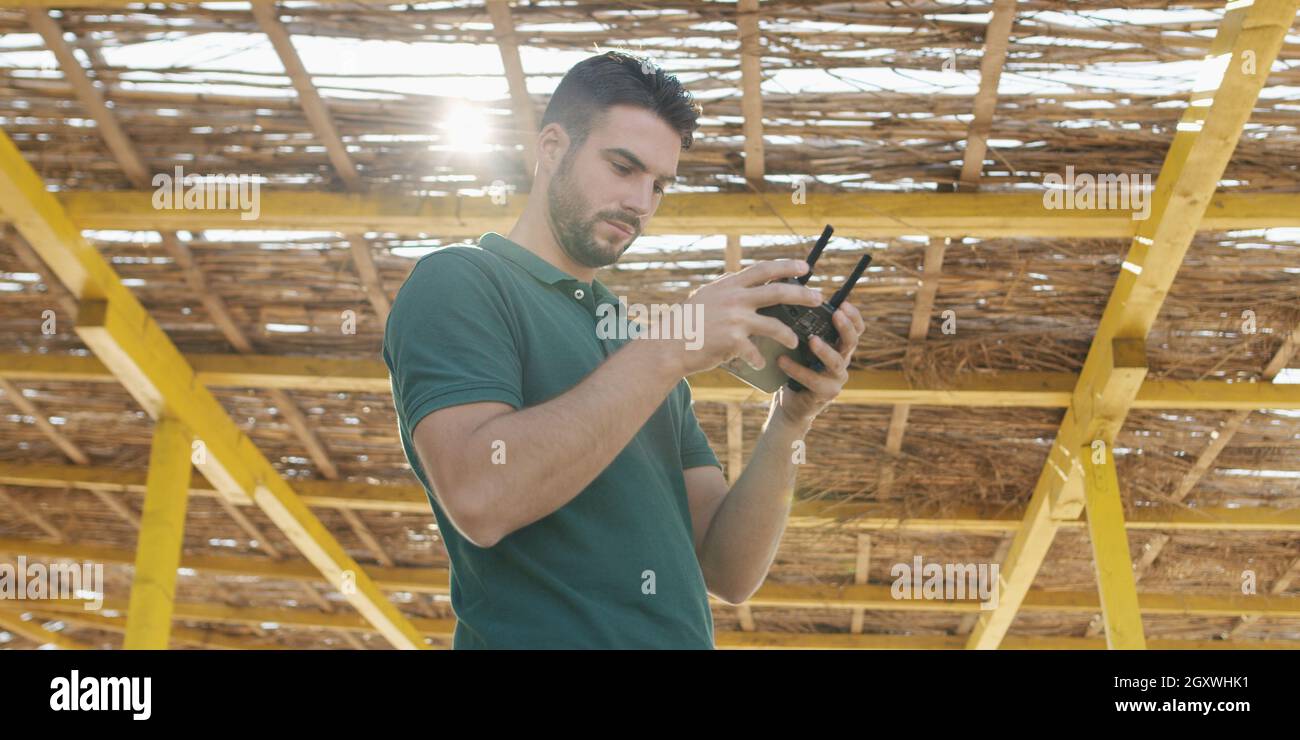 Man operating drone with remote controler by the sea on autumn day ...