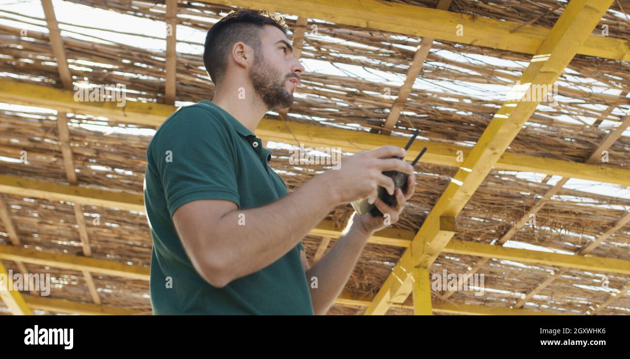 Man operating drone with remote controler by the sea on autumn day ...