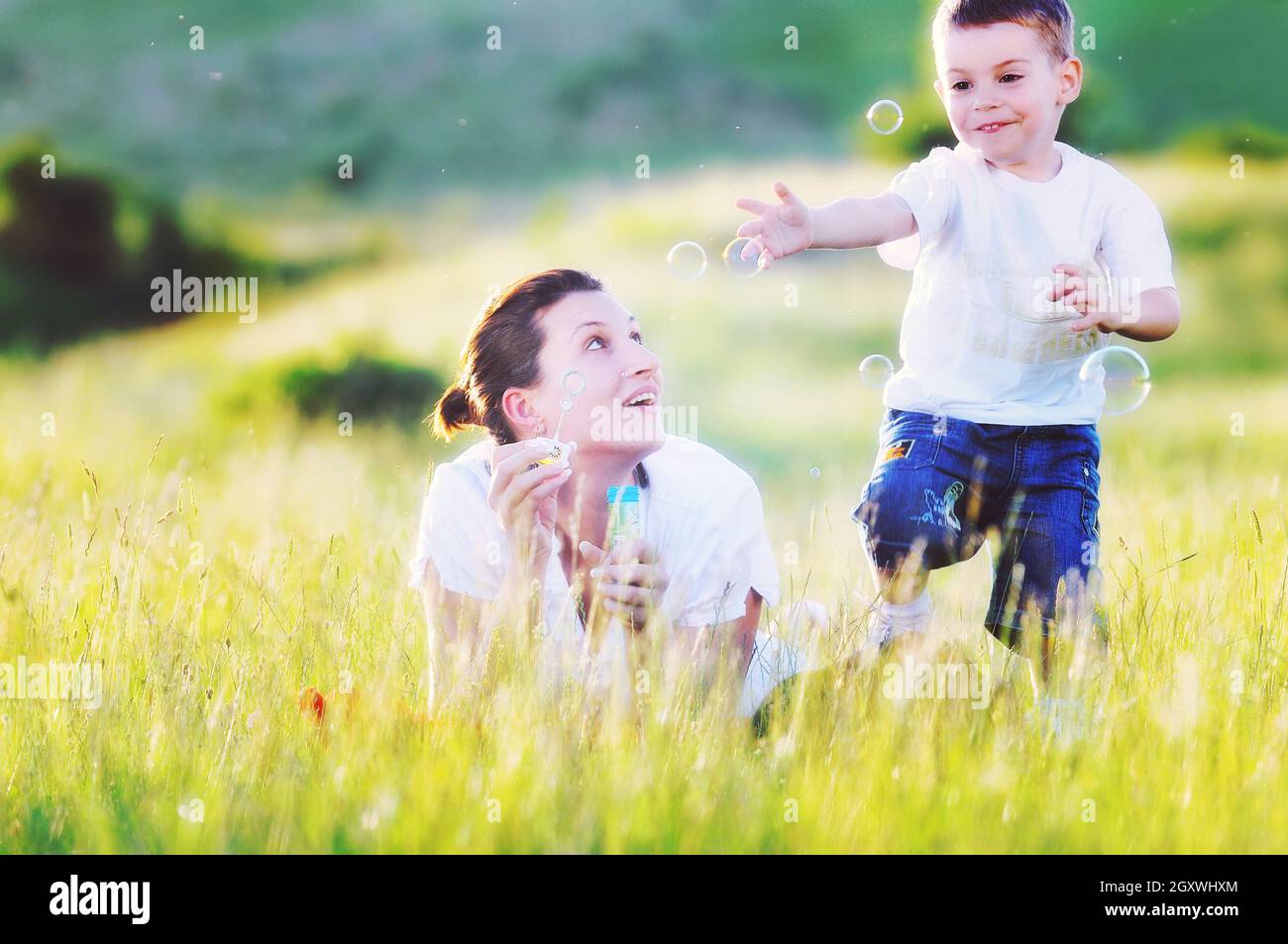 happy child and woman outdoor playing with soap bubble on meadow Stock Photo - Alamy