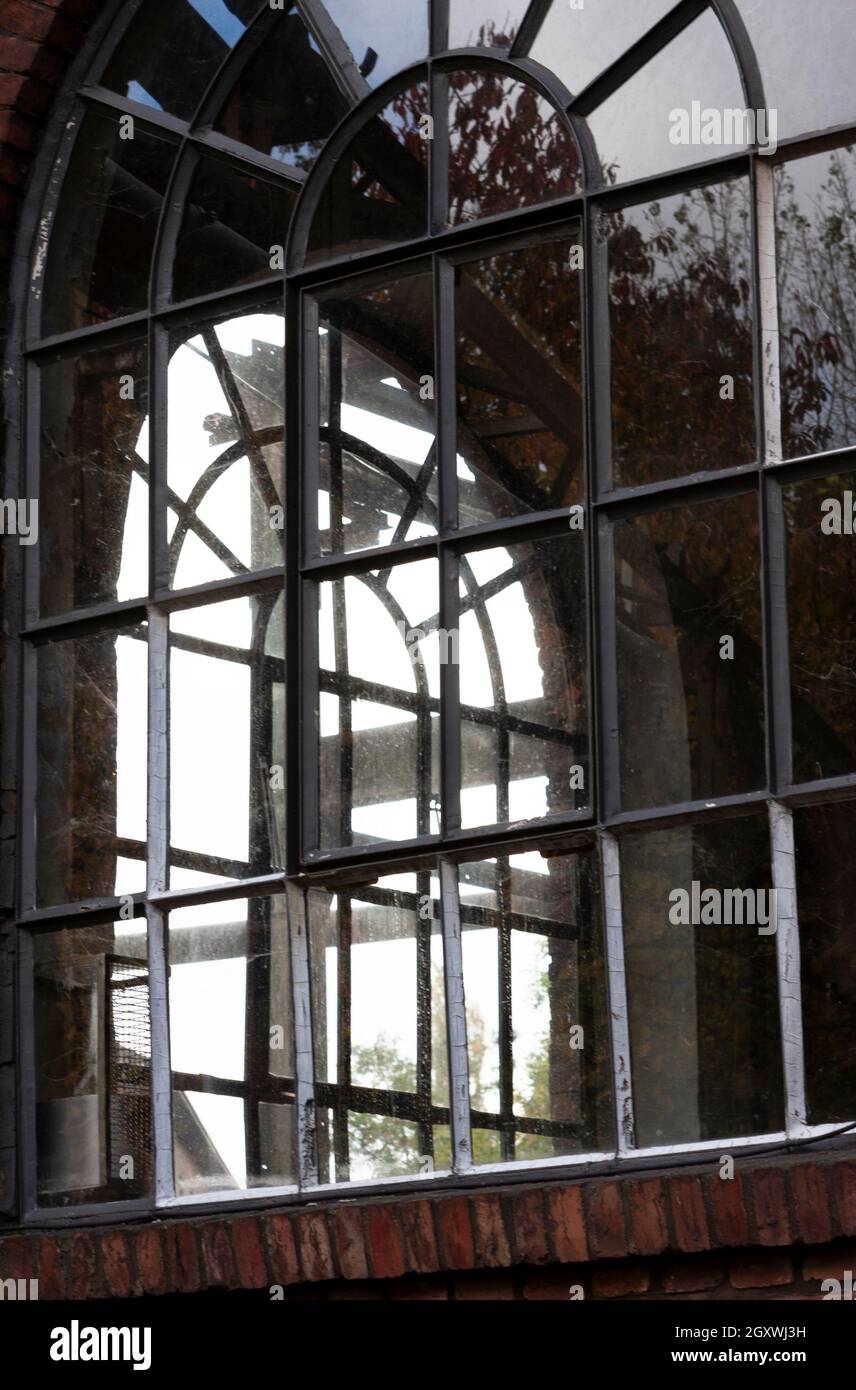 The photo shows a section of an old factory window with round arch ...