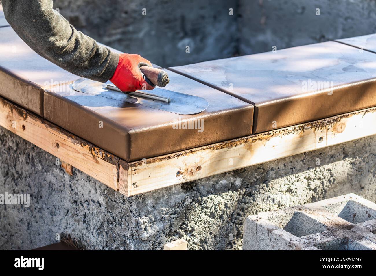 Construction Worker Using Trowel On Wet Cement Forming Coping Around ...