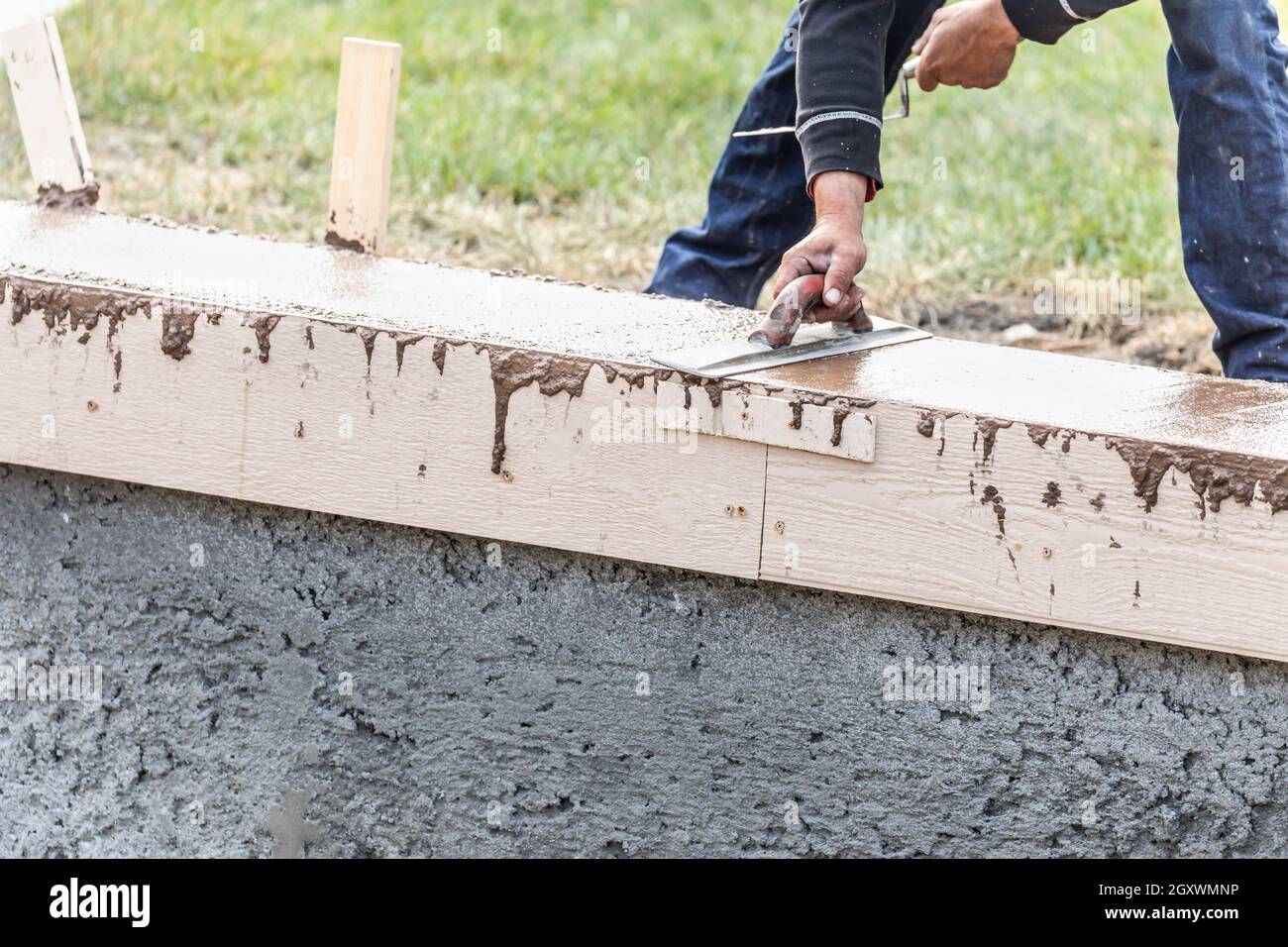 Construction Worker Using Trowel On Wet Cement Forming Coping Around ...