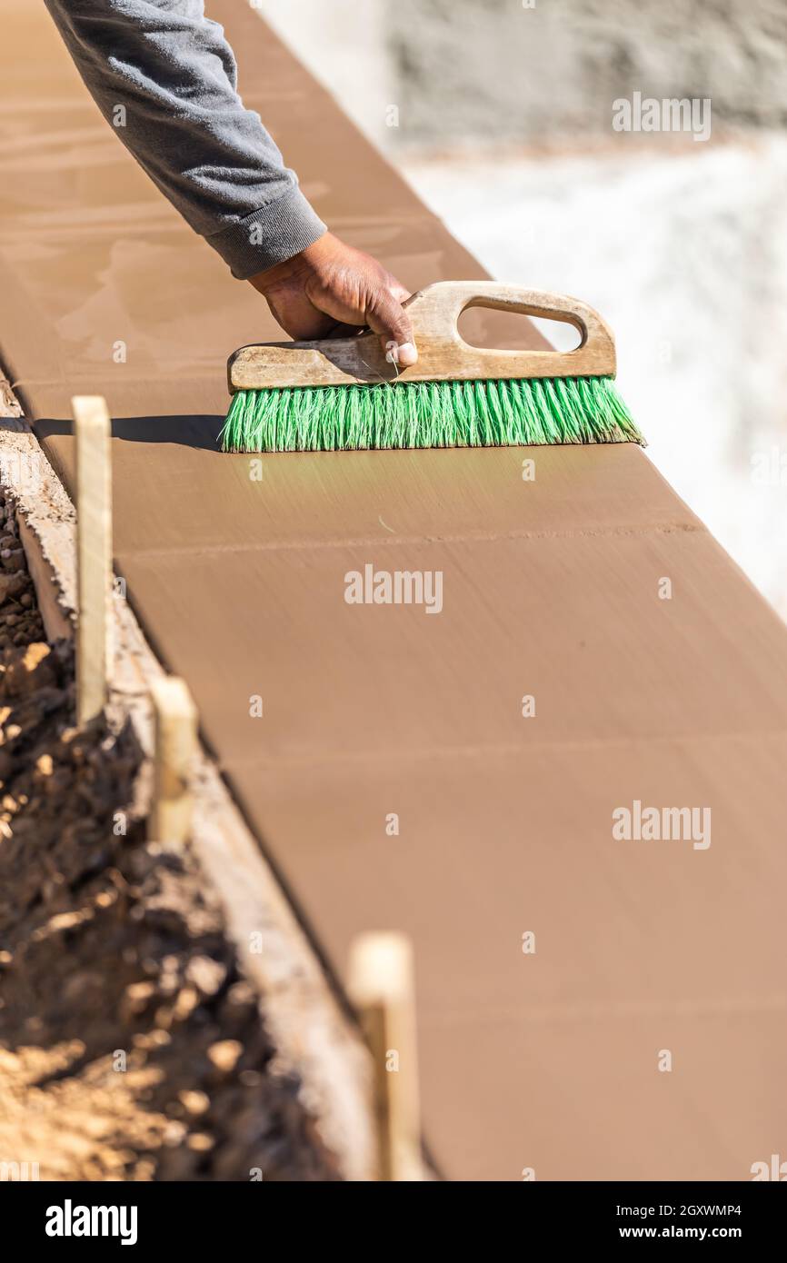 Construction Worker Using Brush On Wet Cement Forming Coping Around New ...