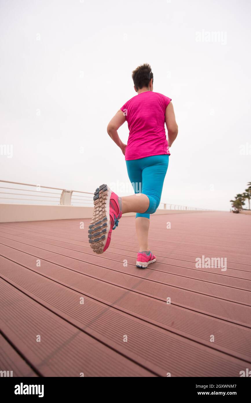very active young beautiful woman busy running on the promenade along ...