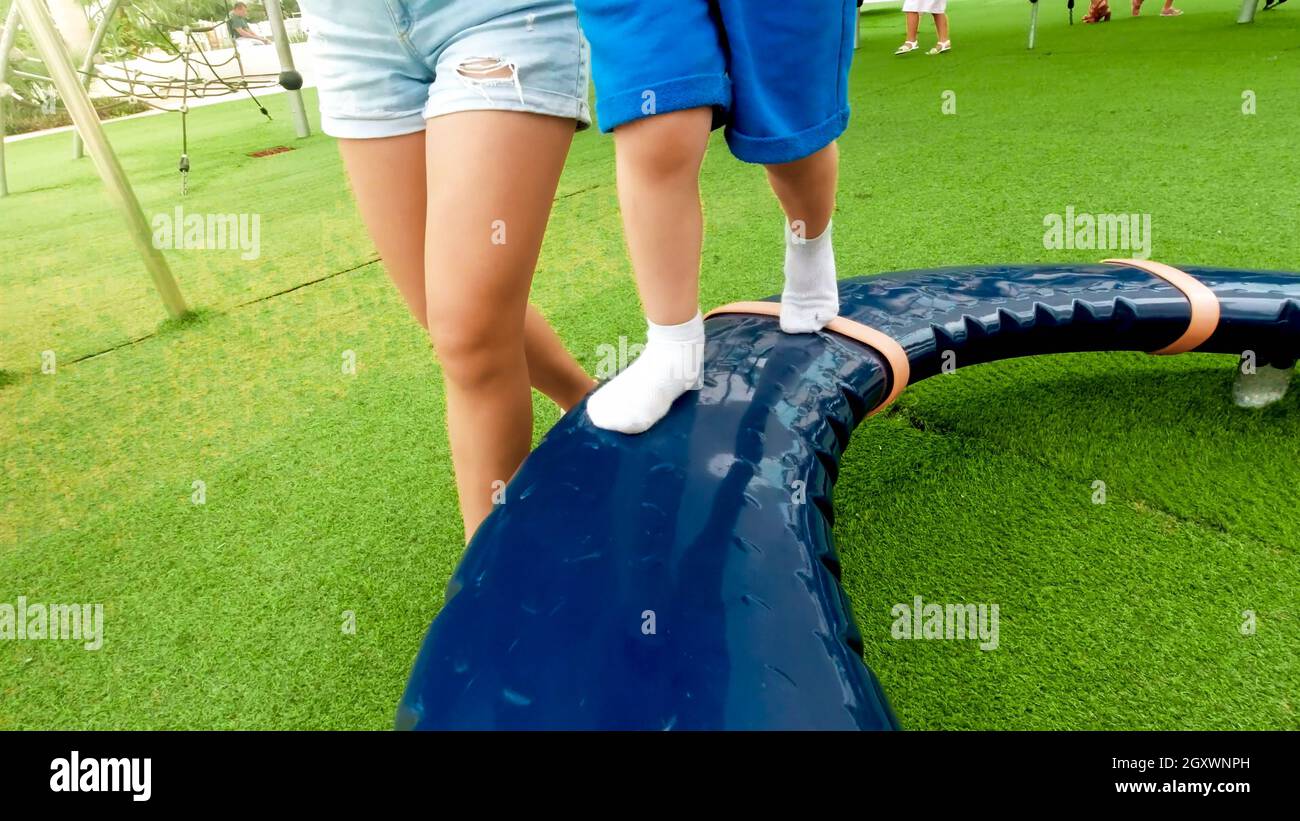 Little child feet walking on balancing board on the playground at park ...