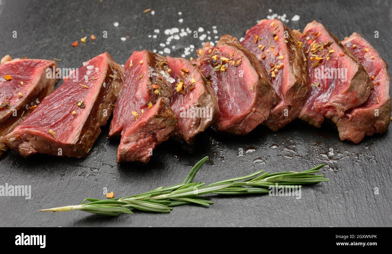 fried beef steaks cut into pieces on a black board, the degree of ...
