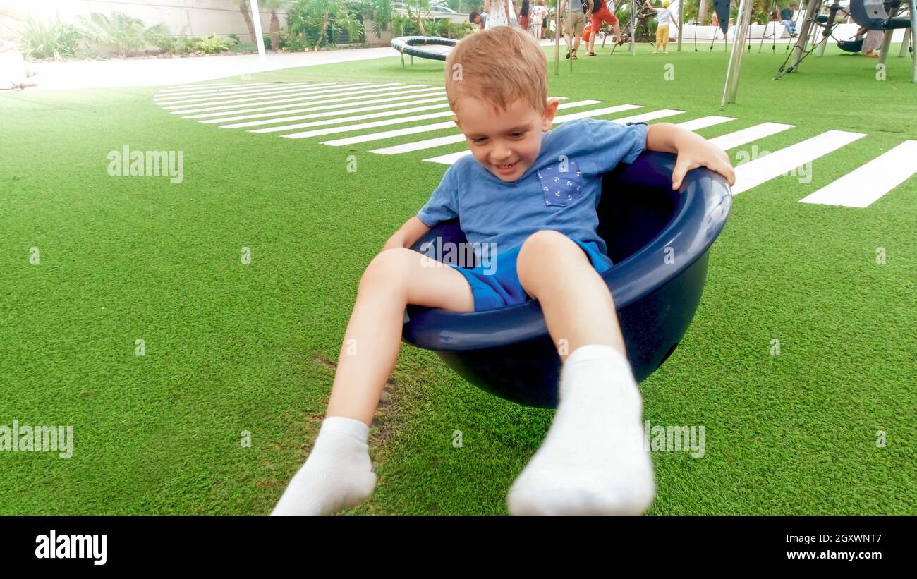 Portrait of cheerful smiling boy spinning in carousel on children ...