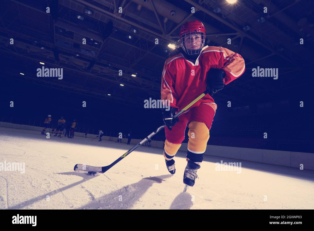 teen girl children ice hockey player in action kicking puck with stick ...