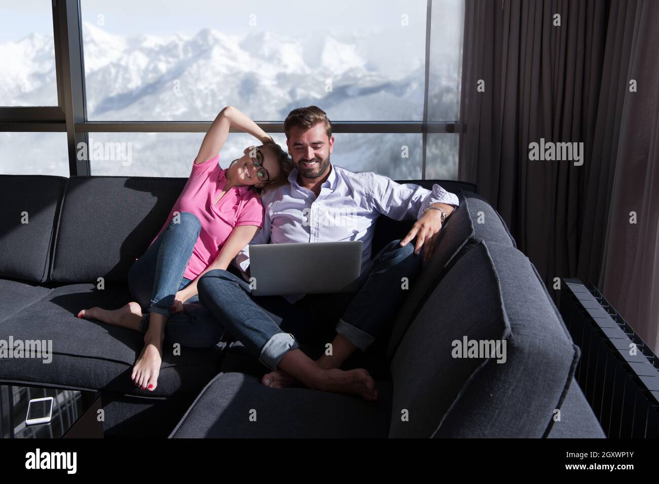 Young couple relaxing at home using laptop computers reading in the ...