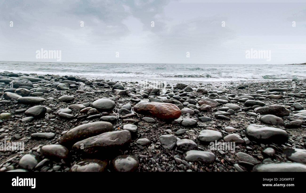 Beautiful landscape of wet pebbles and rocks lying on ocean shore at ...