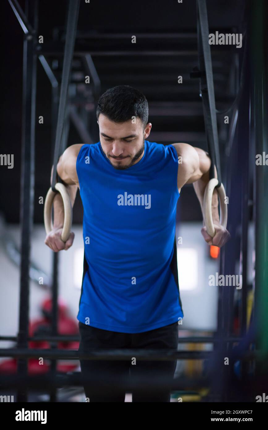 young athlete man working out pull ups with gymnastic rings at the ...