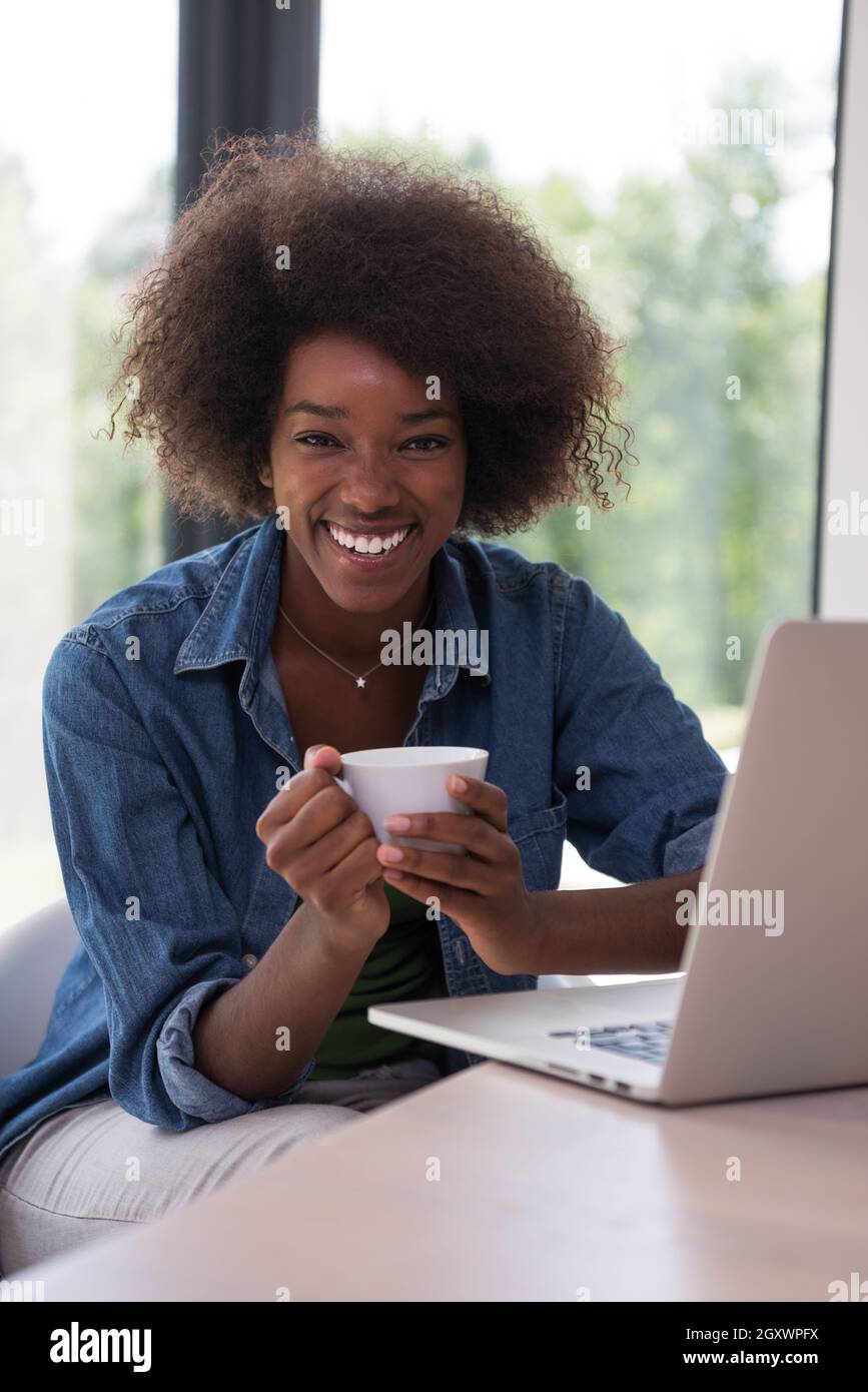 Young african american woman smiling sitting near bright window while ...