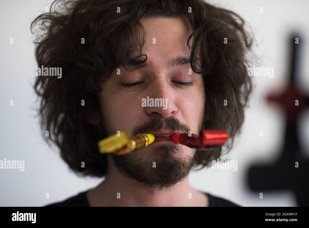 Portrait of a man in party hat blowing in whistle isolated on a white ...