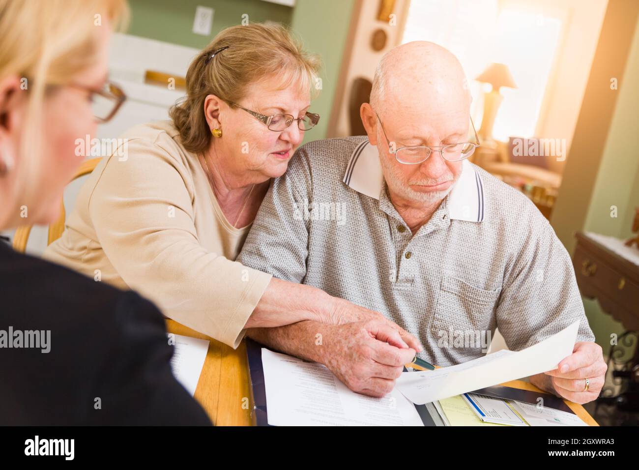 Senior Adult Couple Going Over Documents in Their Home with Agent At ...