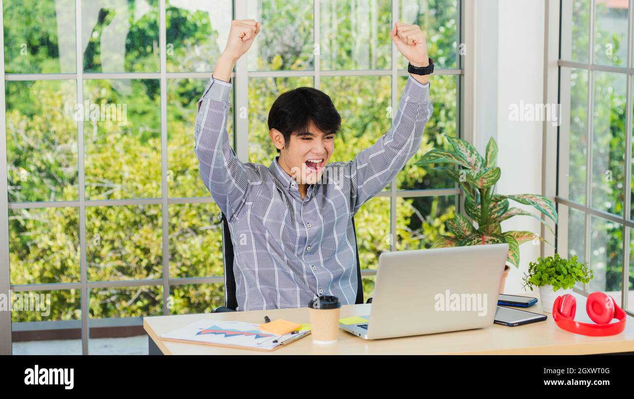 Yes! Happy excited Asian man raising his arm up to celebrate ...