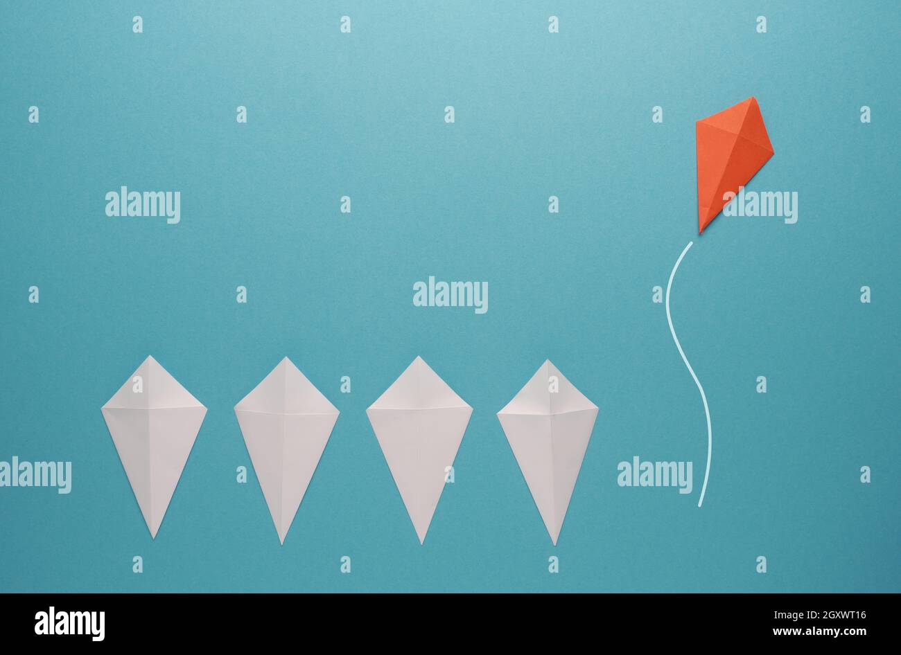 White paper kites in a row with a red paper kite flying away ...