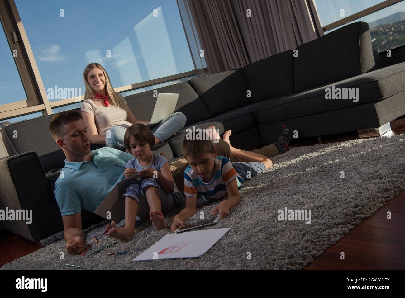Happy Young Family Playing Together at home on the floor using a laptop ...