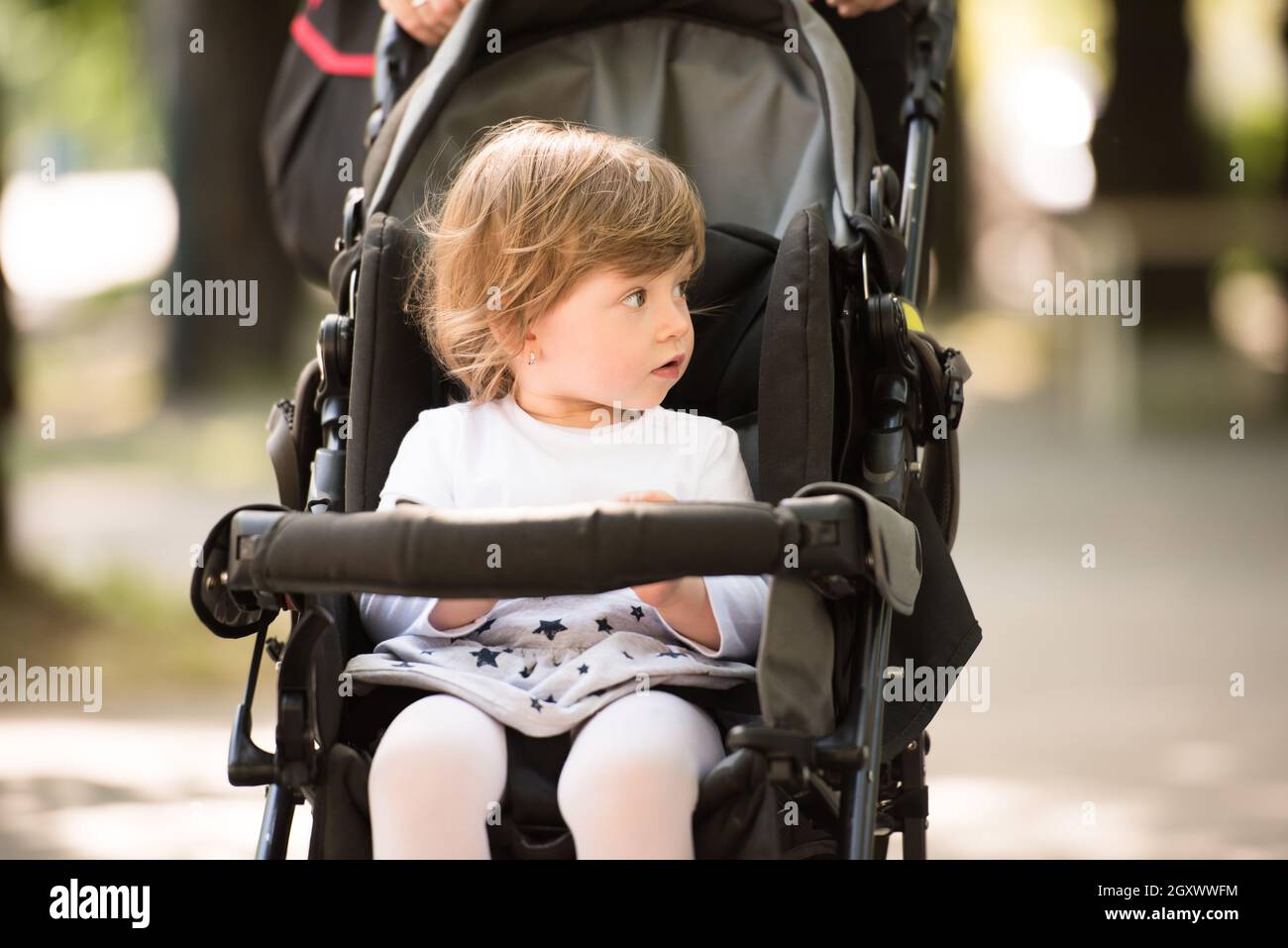little and very beautiful baby girl sitting in the pram and waiting for ...