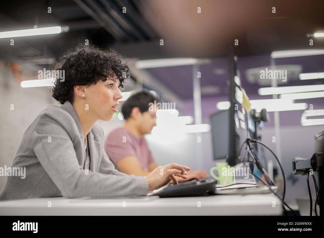young female software developer using desktop computer while writing programming code at modern ...