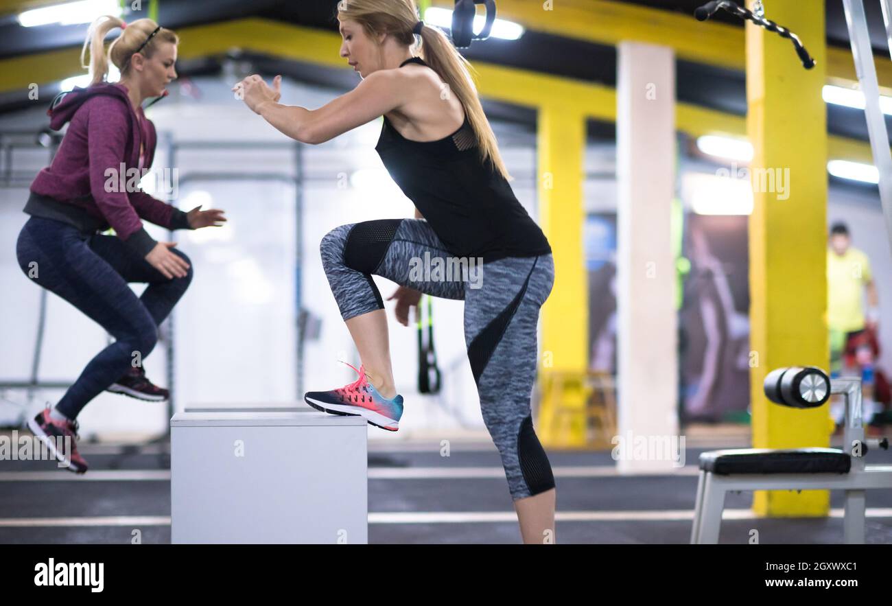 group of young healthy athletic people training jumping on fit box at ...