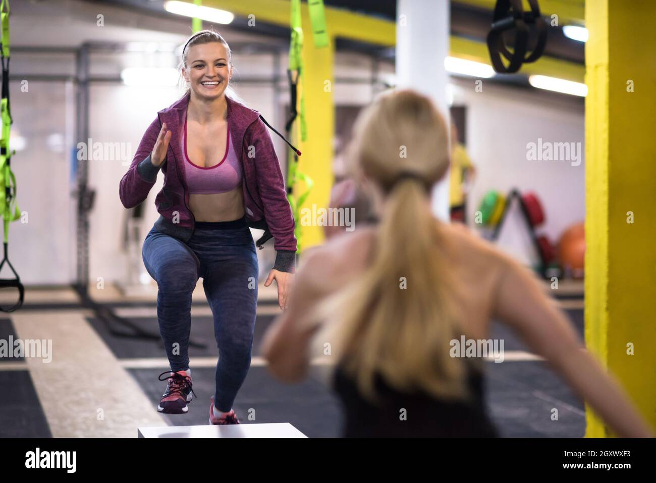 group of young healthy athletic people training jumping on fit box at ...