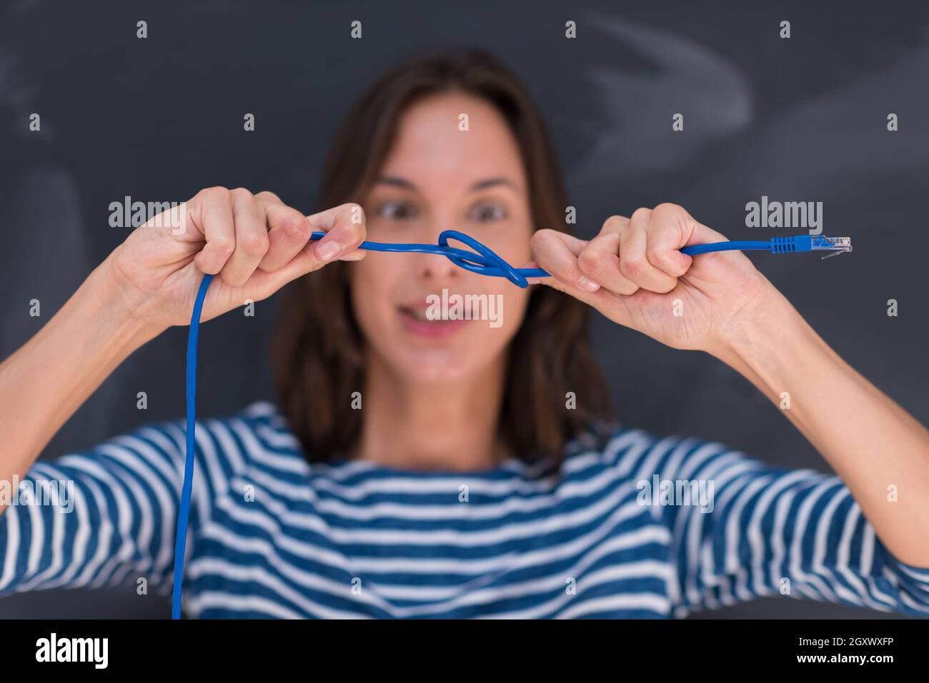 portrait of a young woman holding a internet cable in front of chalk ...