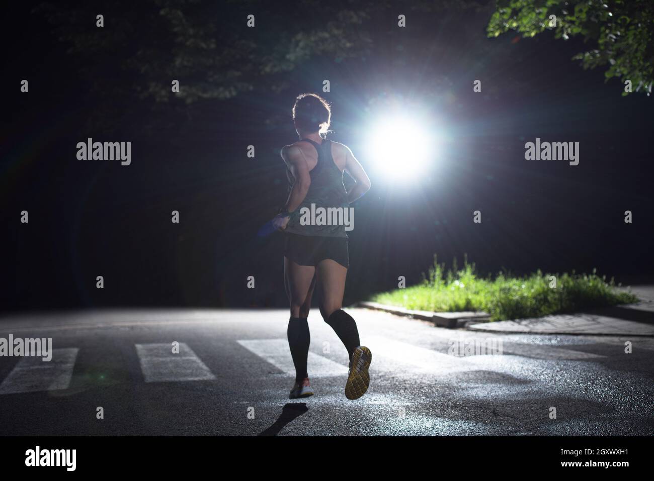 fit muscular female runner training for marathon running at night on ...