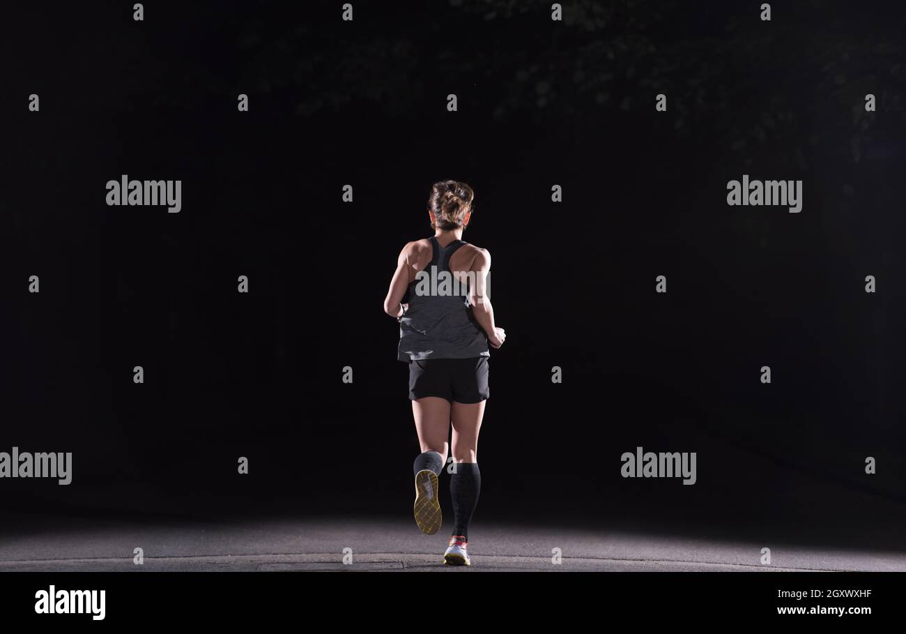 fit muscular female runner training for marathon running at night on ...
