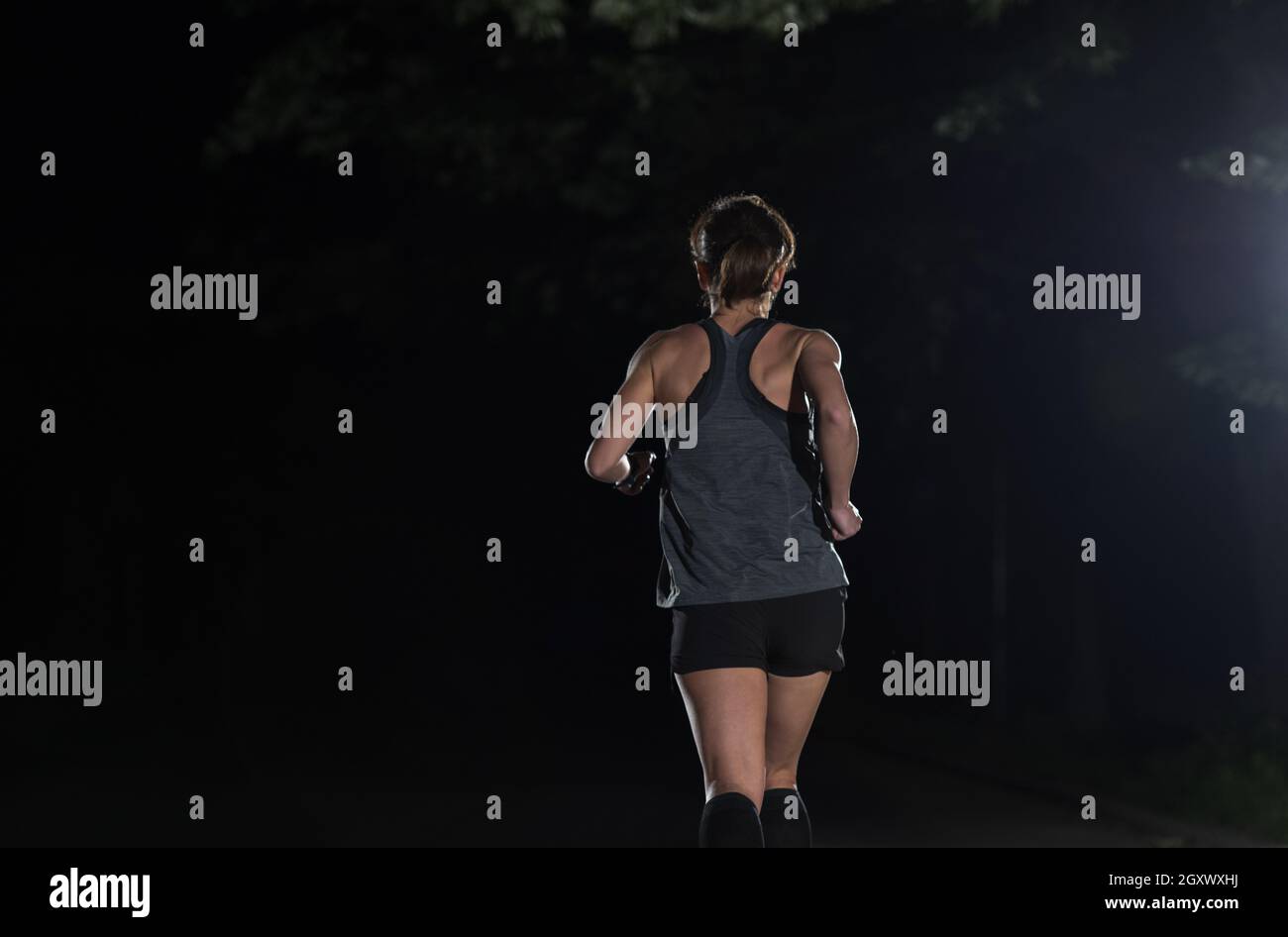 fit muscular female runner training for marathon running at night on ...