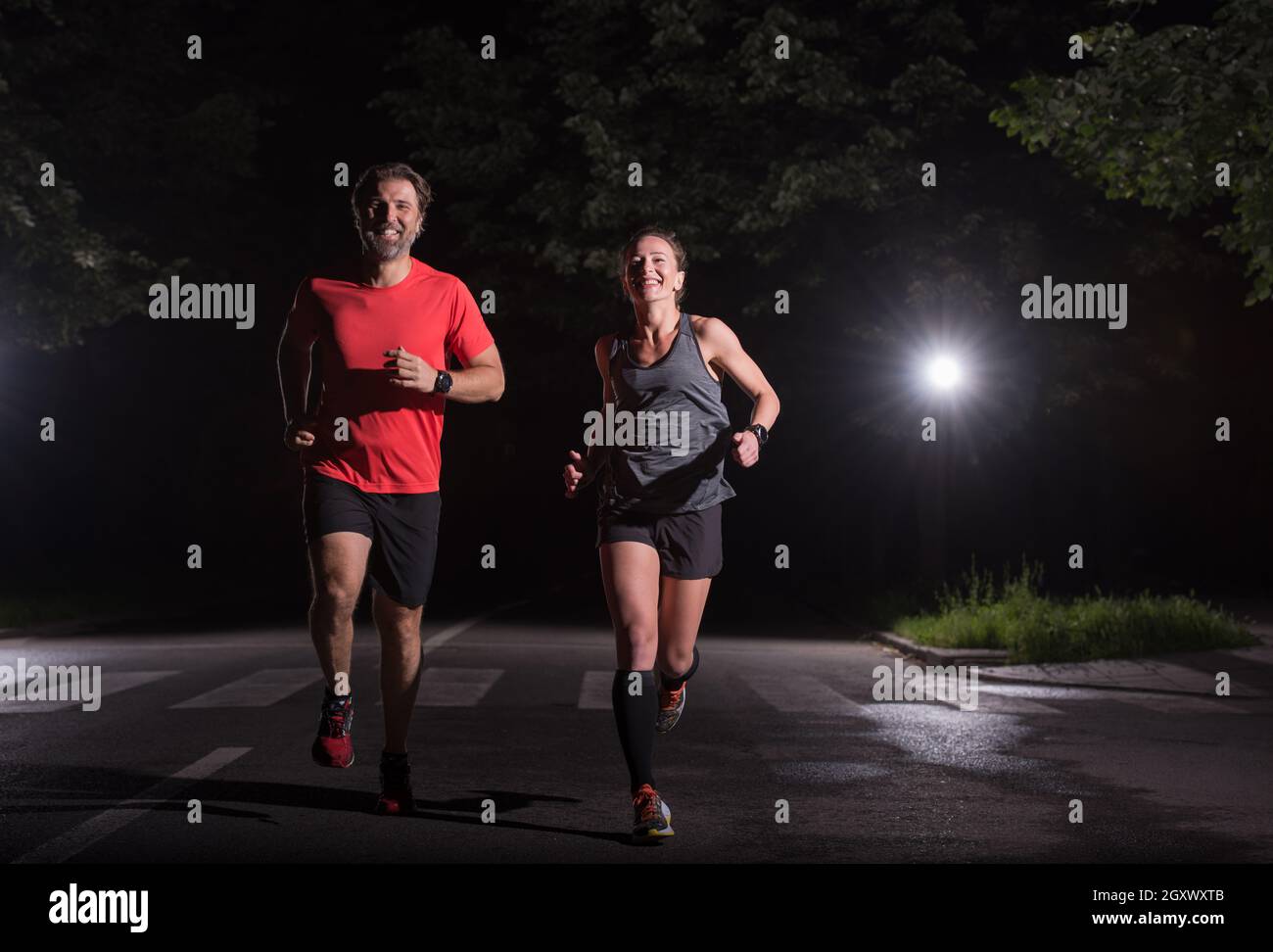 group of healthy people jogging in city park, runners team at night ...