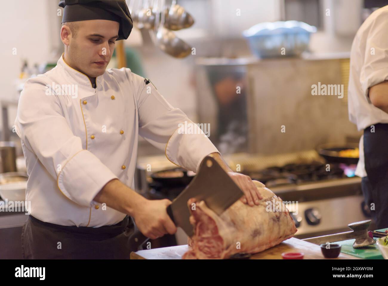 chef using ax while cutting big piece of beef on wooden board in ...