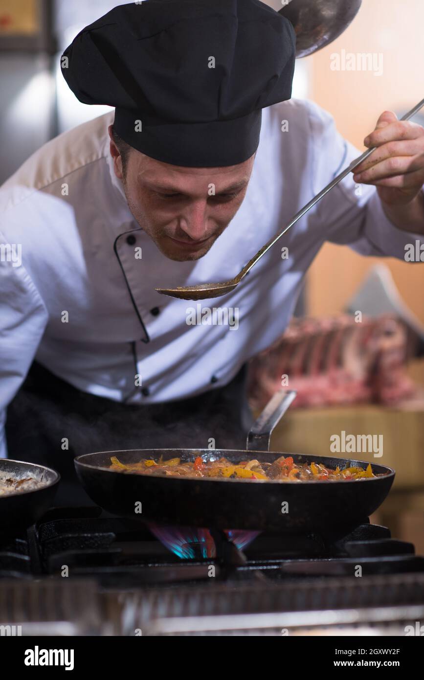 Handsome chef tasting food with spoon at the restaurant kitchen Stock ...