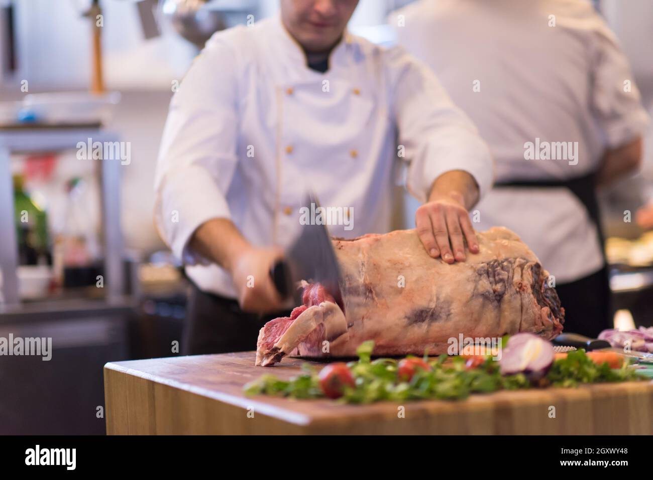chef using ax while cutting big piece of beef on wooden board in ...